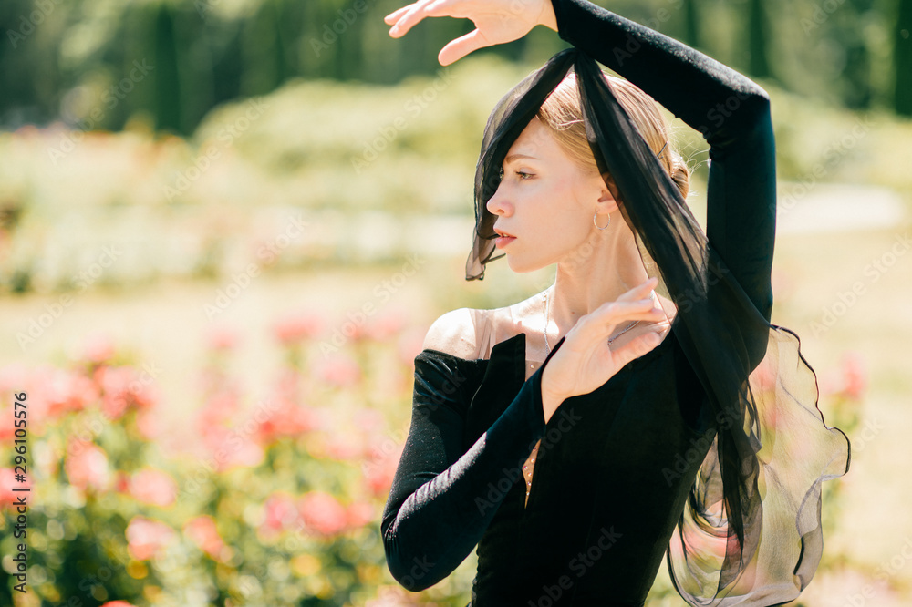 Eccentric woman in black dress with veil on her sleeve posing in summer ...