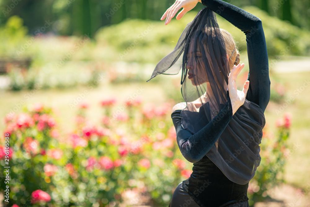 Eccentric woman in black dress with veil on her sleeve posing in summer ...