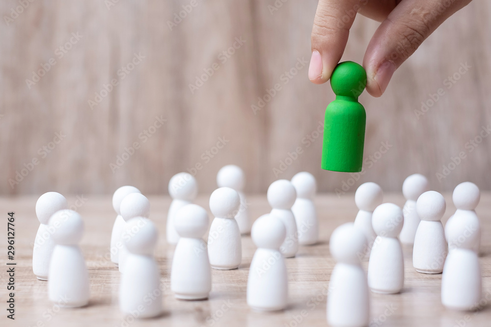 Businessman hand pulling Green leader man wooden from crowd of ...