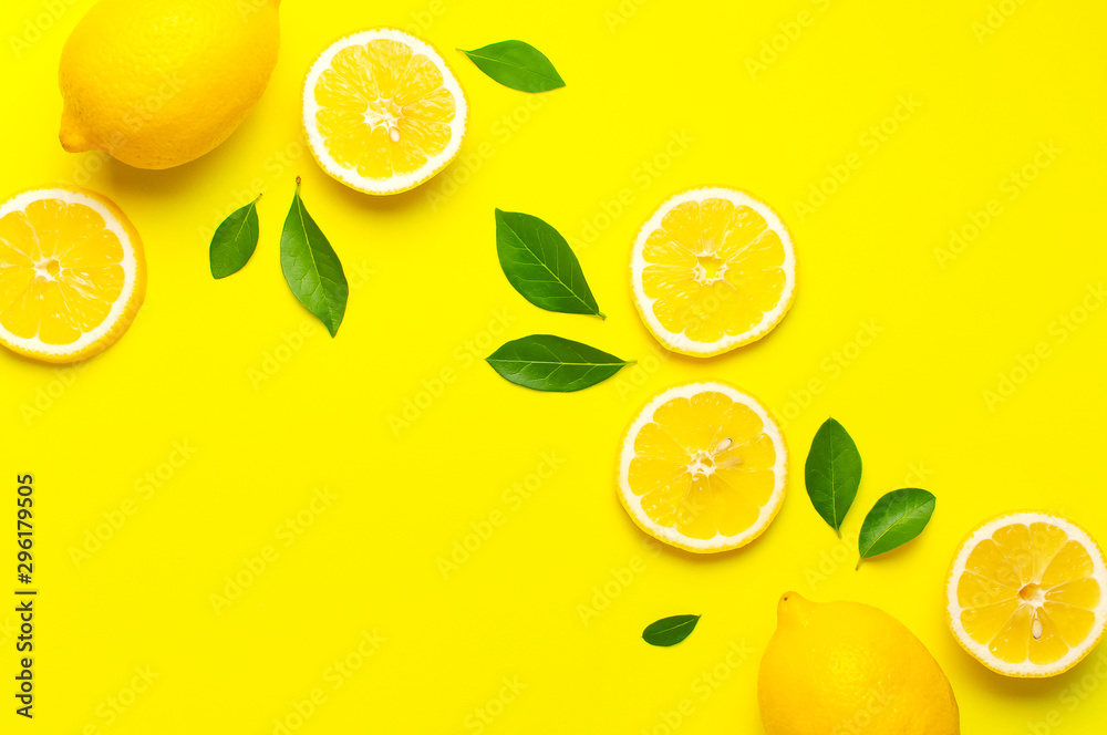 Creative background with fresh lemons and green leaves on bright yellow ...