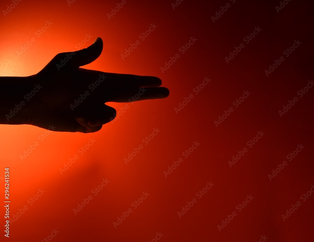 the human hand making a shape of pointed hand gun on a red background ...