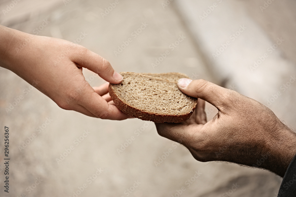 Woman giving poor homeless person pieces of bread outdoors, closeup ...