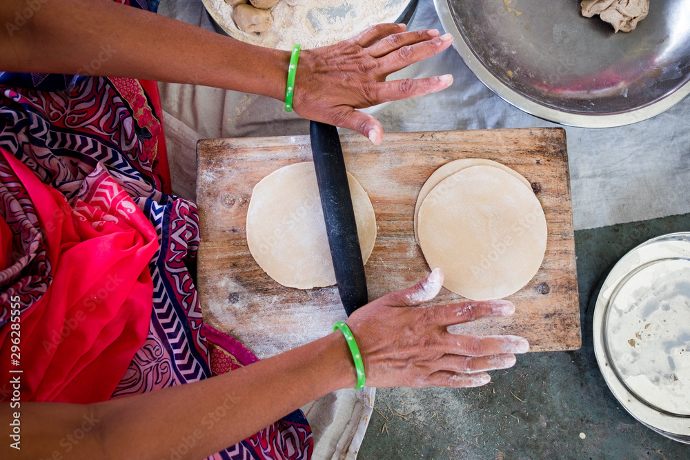 above view of young indian woman making fresh homemade rotis and ...