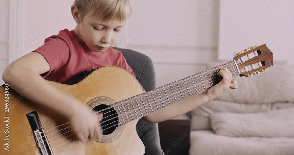 Young boy strumming a guitar. Boy of 8 years plays the classical guitar ...