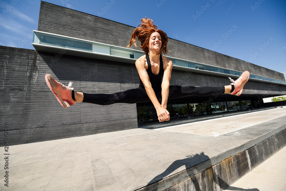 Happy sporty young woman jumping at a modern building Stock Photo ...