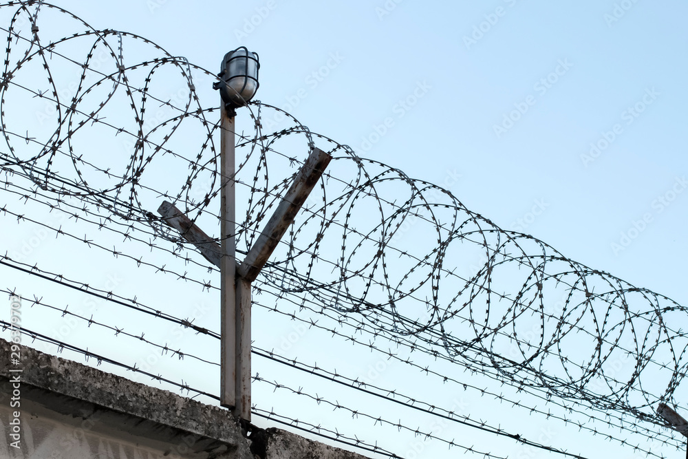 Barbed wire on an old shattered gray concrete fence and a lantern on a ...