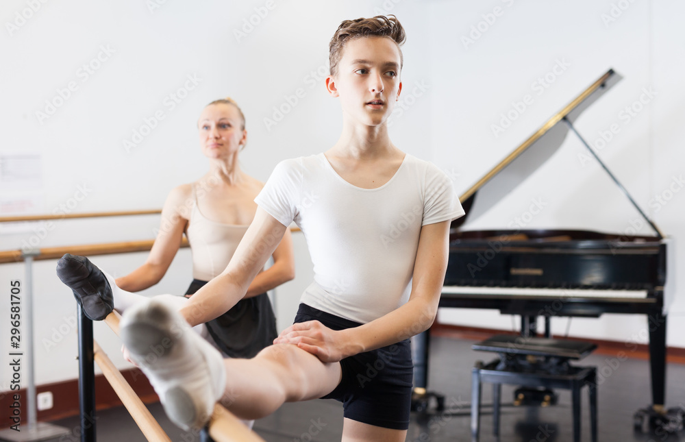 Choreographer woman and young man do exercises at ballet bar in hall ...