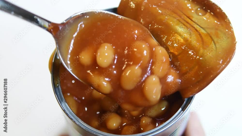 Close up of spoon appearing with open tin of British baked beans ...
