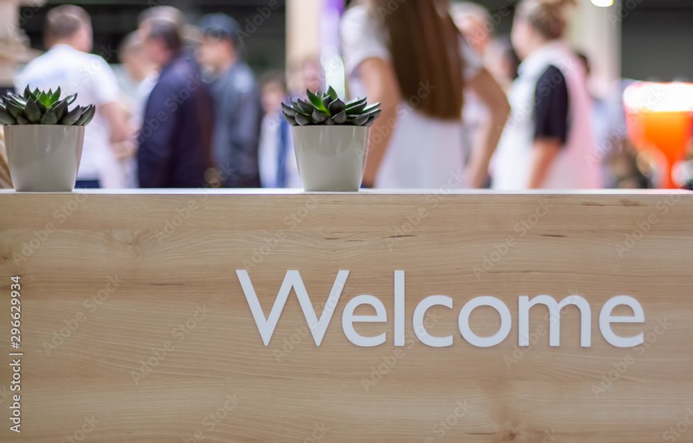 light wooden reception stand with a white inscription welcome. on a ...
