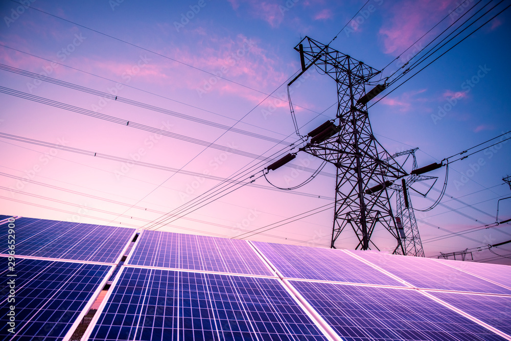 Solar photovoltaic panels and transmission towers at sunset ...