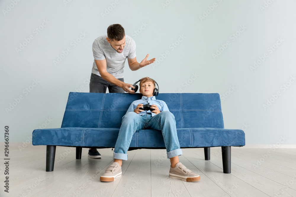 Little boy playing videogame and ignoring his angry father at home ...