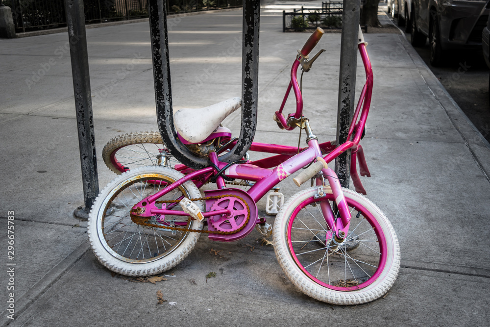 Two old girl's bicycles, rusty and long forgotten, chained to a bike ...