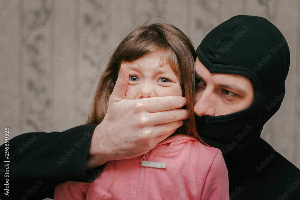 A man in a black mask covers the mouth of a little girl. The thug takes hostage baby. The ...