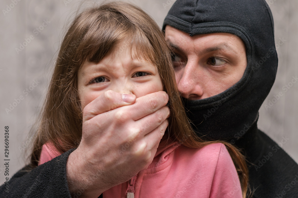 Portrait of a gangster and scared child. A man in a black mask covers ...