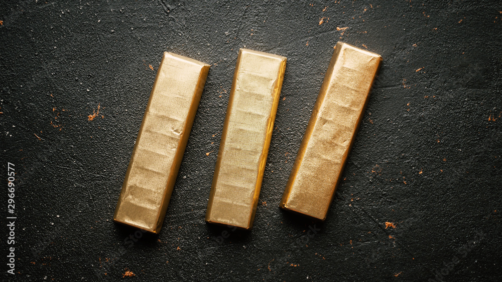 Three chocolate bars in gold foil on black concrete Stock Photo | Adobe ...