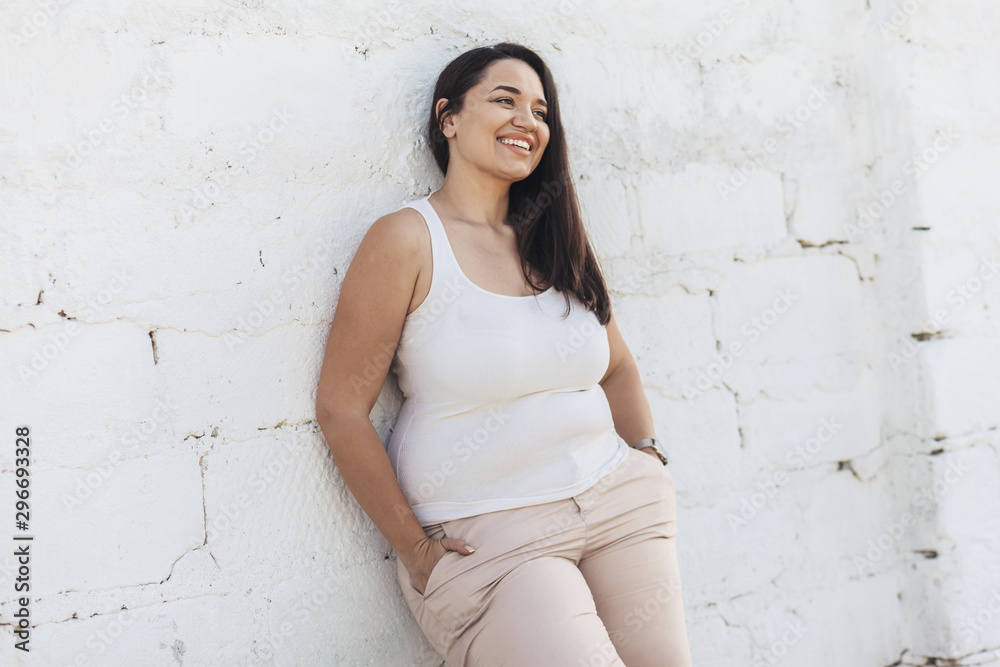Plus size model dressed in white shirt posing over brick wall Stock Photo | Adobe Stock