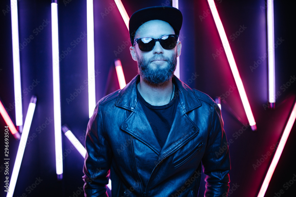 Hipster handsome man on the city streets being illuminated by neon ...