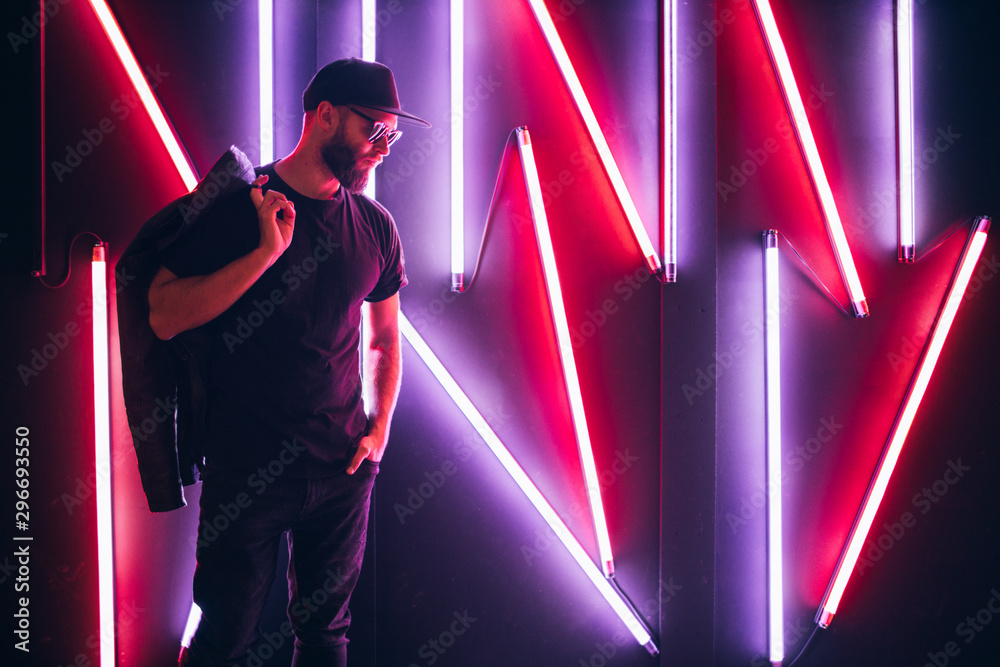 Hipster handsome man on the city streets being illuminated by neon ...