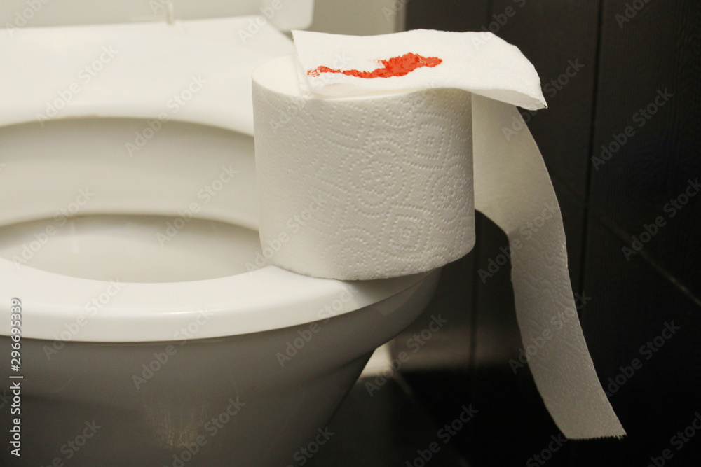A roll of toilet paper with blood lies on the toilet. The concept of ...