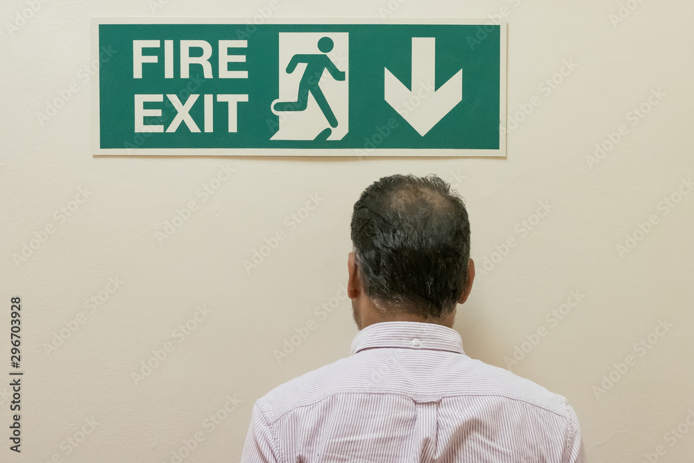 Man seen walking into a solid wall, below a Fire Exit sign located in ...
