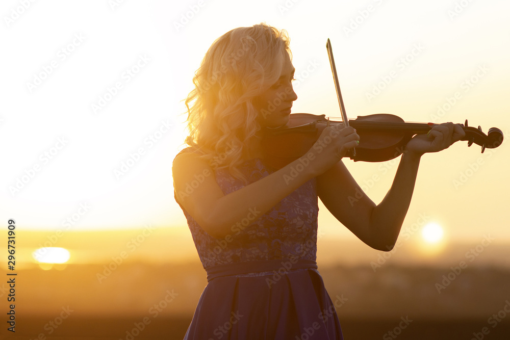 romantic portrait of girl playing violin at sunset in field, woman ...
