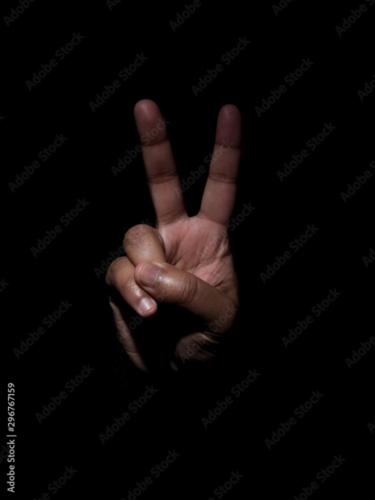 Low key photo of a man showing two fingers indicating the number two or ...