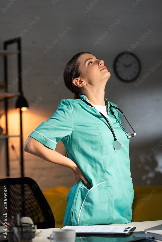 attractive nurse in uniform having back pain during night shift Stock ...