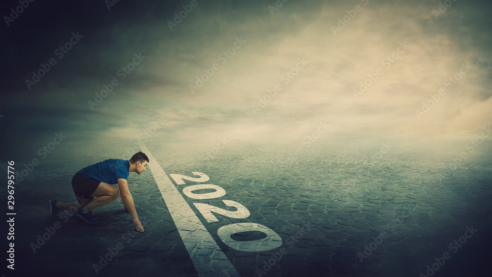 Determined man stands in running position, at the start line, looking ...