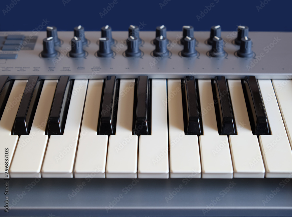 Electronic synthesizer keyboard with many control knobs on blue ...