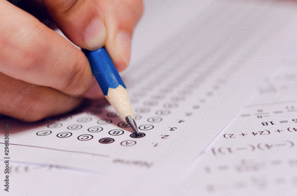 Students hand holding pencil writing selected choice on answer sheets ...