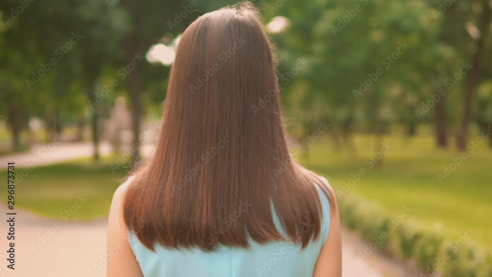 b roll rear female with long hair walks on pedestrian zone along alley ...