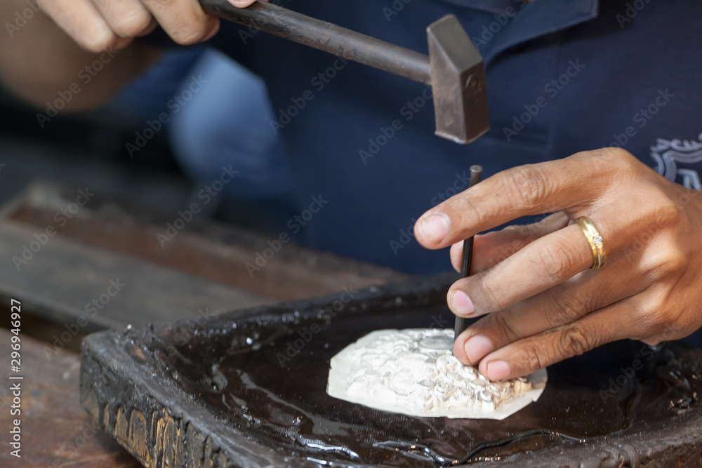 Silversmith using hammers and steel engraved pattern on silver plate ...