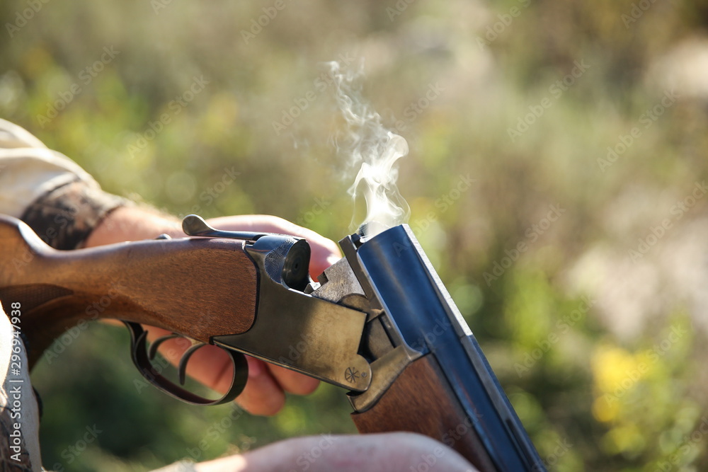 smoking rifle in hunter's hands close up. hunter's hand takes out a ...