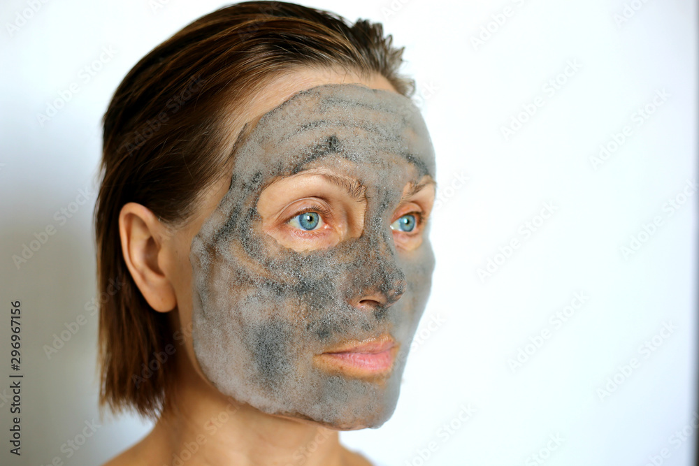 Beautiful Mature woman making face bubble charcoal mask. Surprised face ...