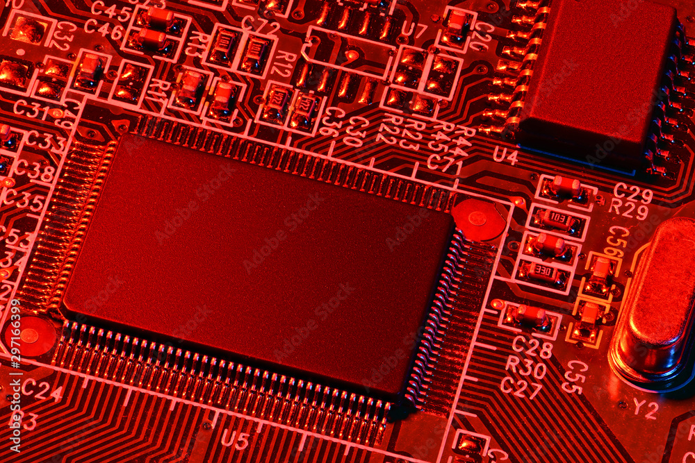 printed circuit board and microchip, or cpu, in red light closeup ...