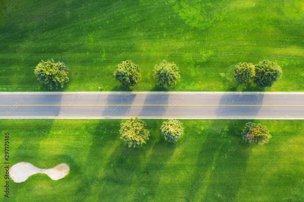 Aerial view of road through beautiful green field at sunset in autumn ...
