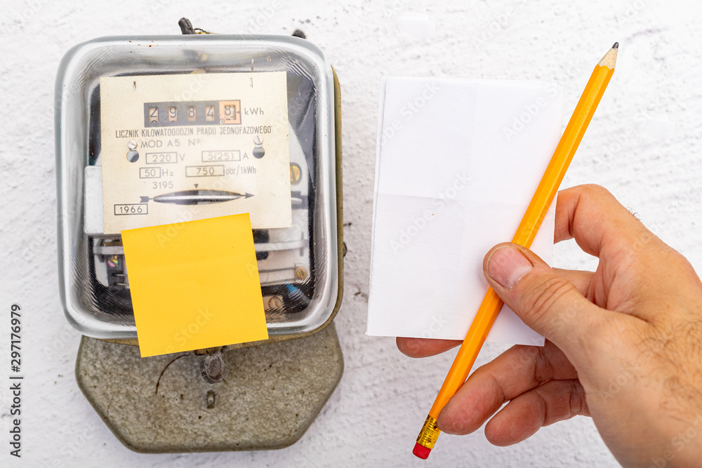 Electricity meter and white paper in hand. A device for measuring the ...