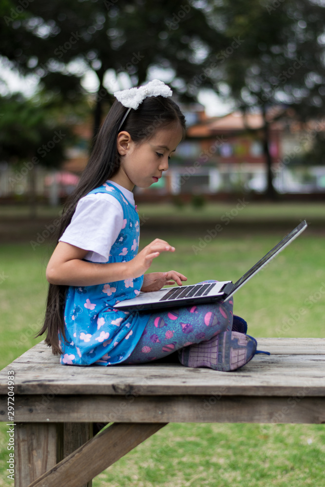 girl studies on her computer in the schoolyard Stock Photo | Adobe Stock