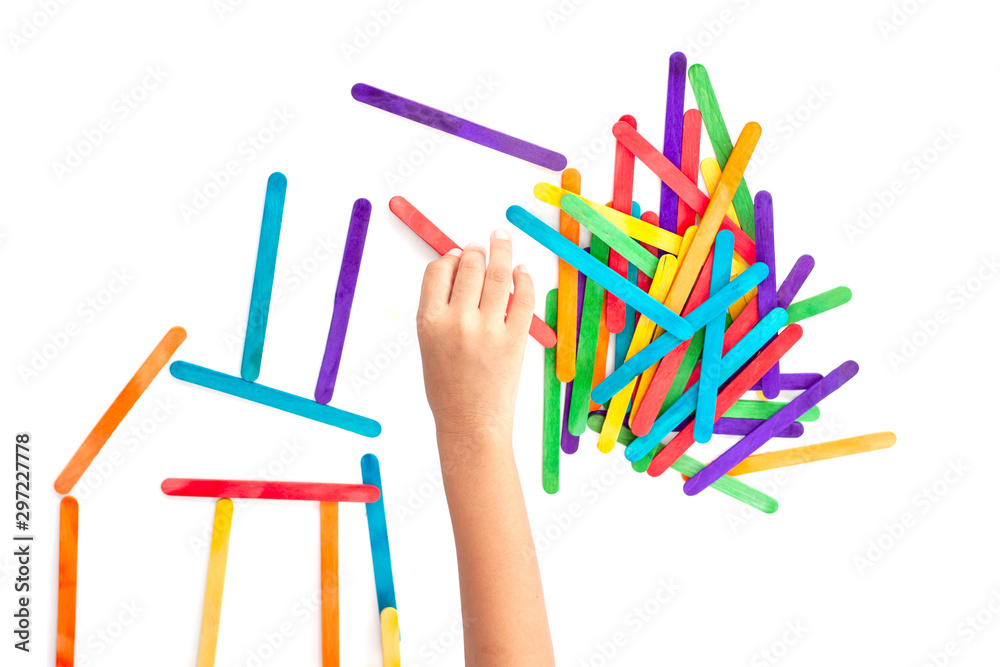 Hand of children is connecting the colorful popsicle sticks joyfully ...
