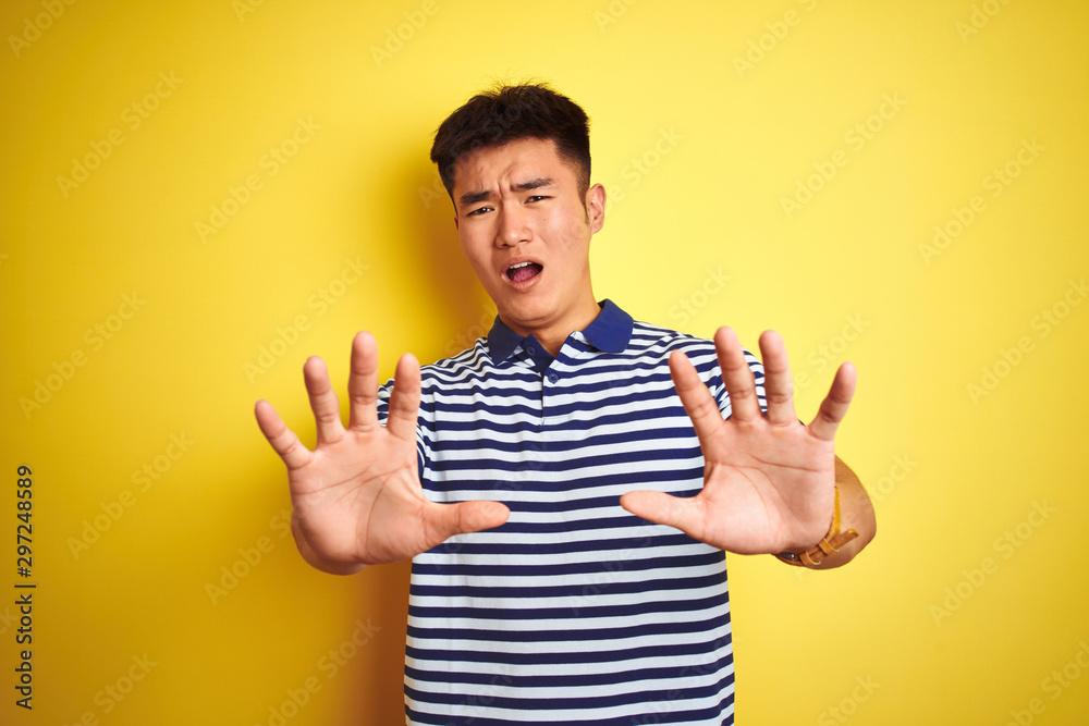 Young asian chinese man wearing striped polo standing over isolated ...