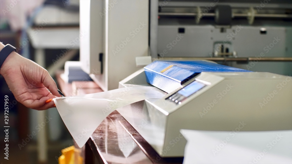 Putting and insert laminating film with paper in laminator. Woman ...