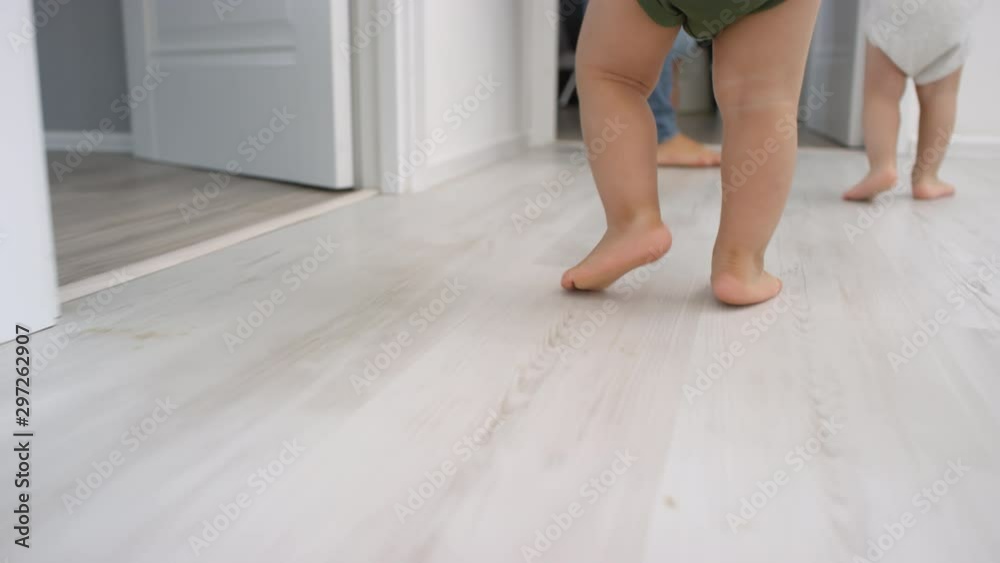 Rear follow shot of legs of unrecognizable barefoot toddler triplets ...