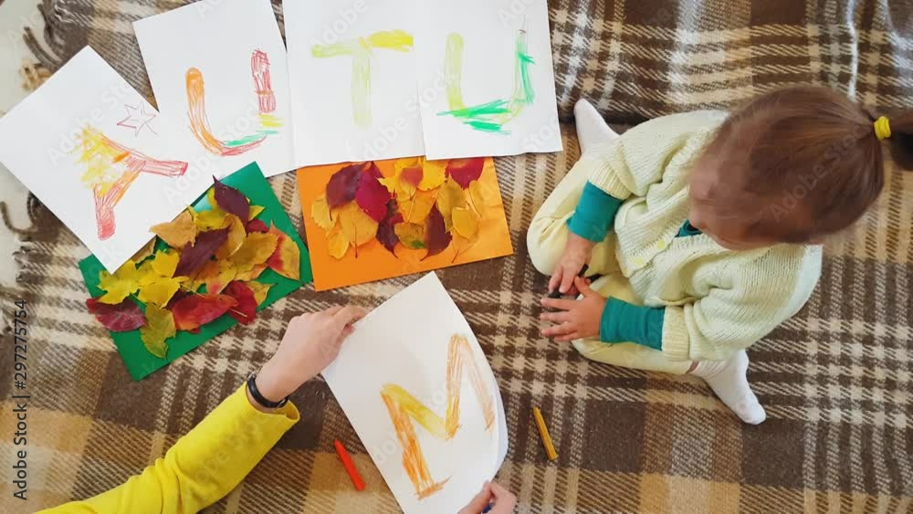 Young mother and daughter draw oil pastels inscription Autumn on white ...