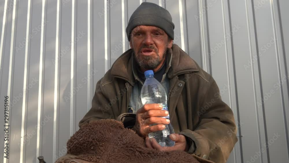 Homeless man holding a plastic bottle of water. 50 year old wretched ...
