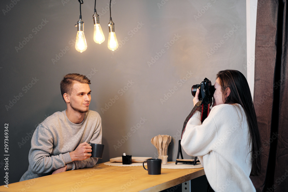 Young female photographer photographs a male model in a home setting ...