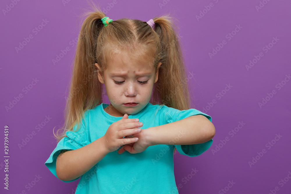 Upset little child girl wounded her hand and cries on a purple ...