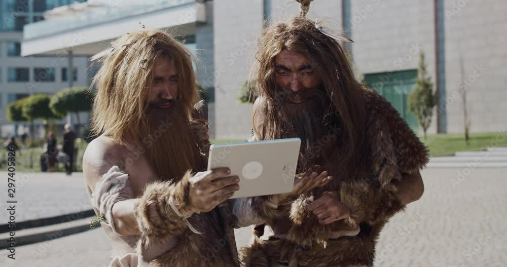 Vidéo Stock Caveman in animal fur using modern tablet browsing internet ...