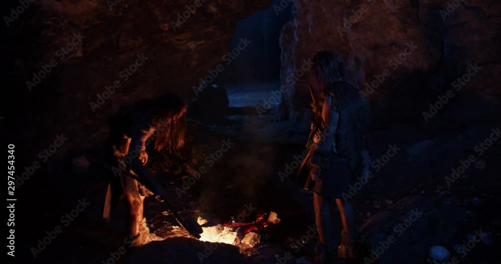Shot back cavemen neanderthals wearing animal skin at dark night stand ...