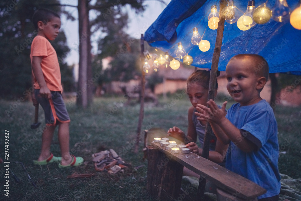 Kids making a small tent with candles and lampions in the backyard ...