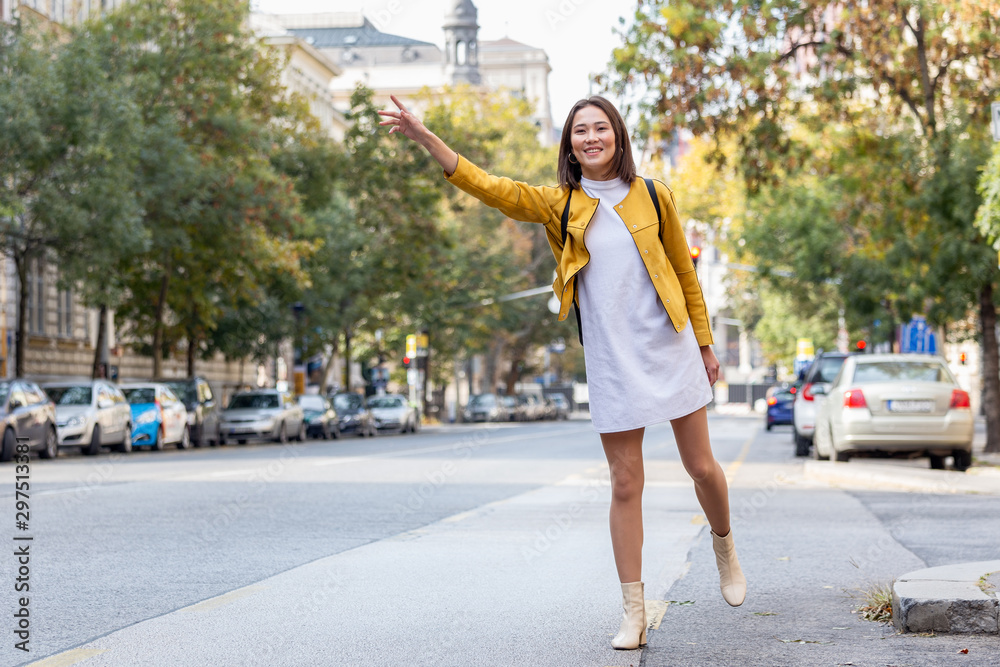 Young woman hailing a taxi ride. Beautiful charming woman hailing a ...